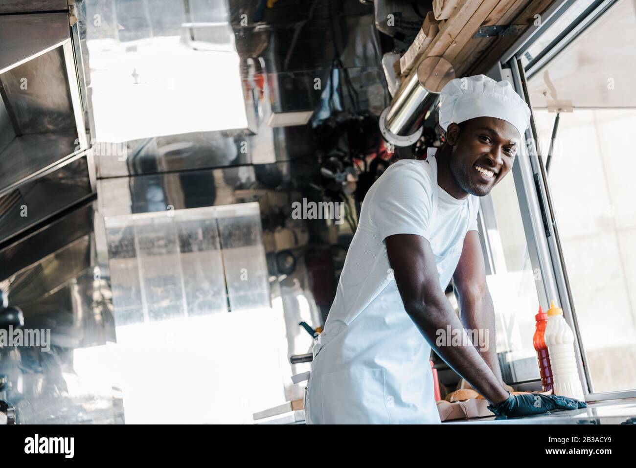 selective focus of happy african american chef smiling in food truck ...