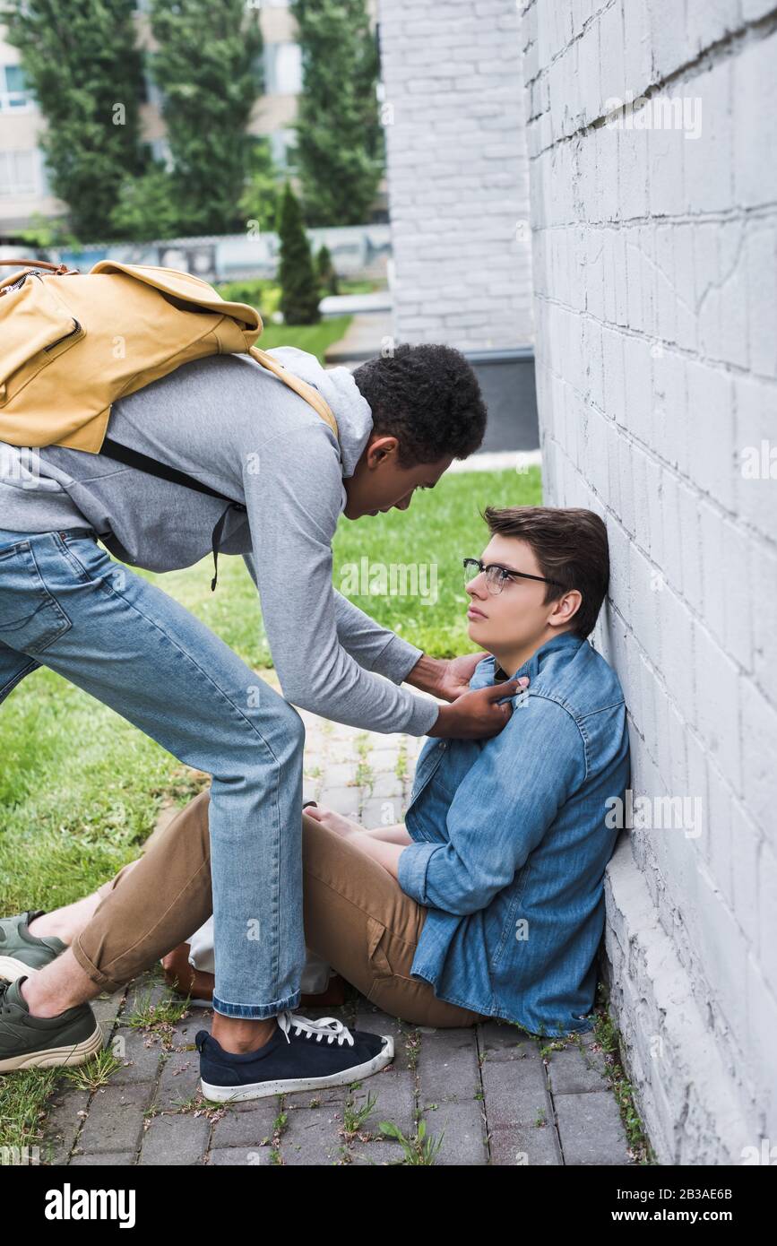 aggressive and brunette african american boy bulling frightened boy in ...