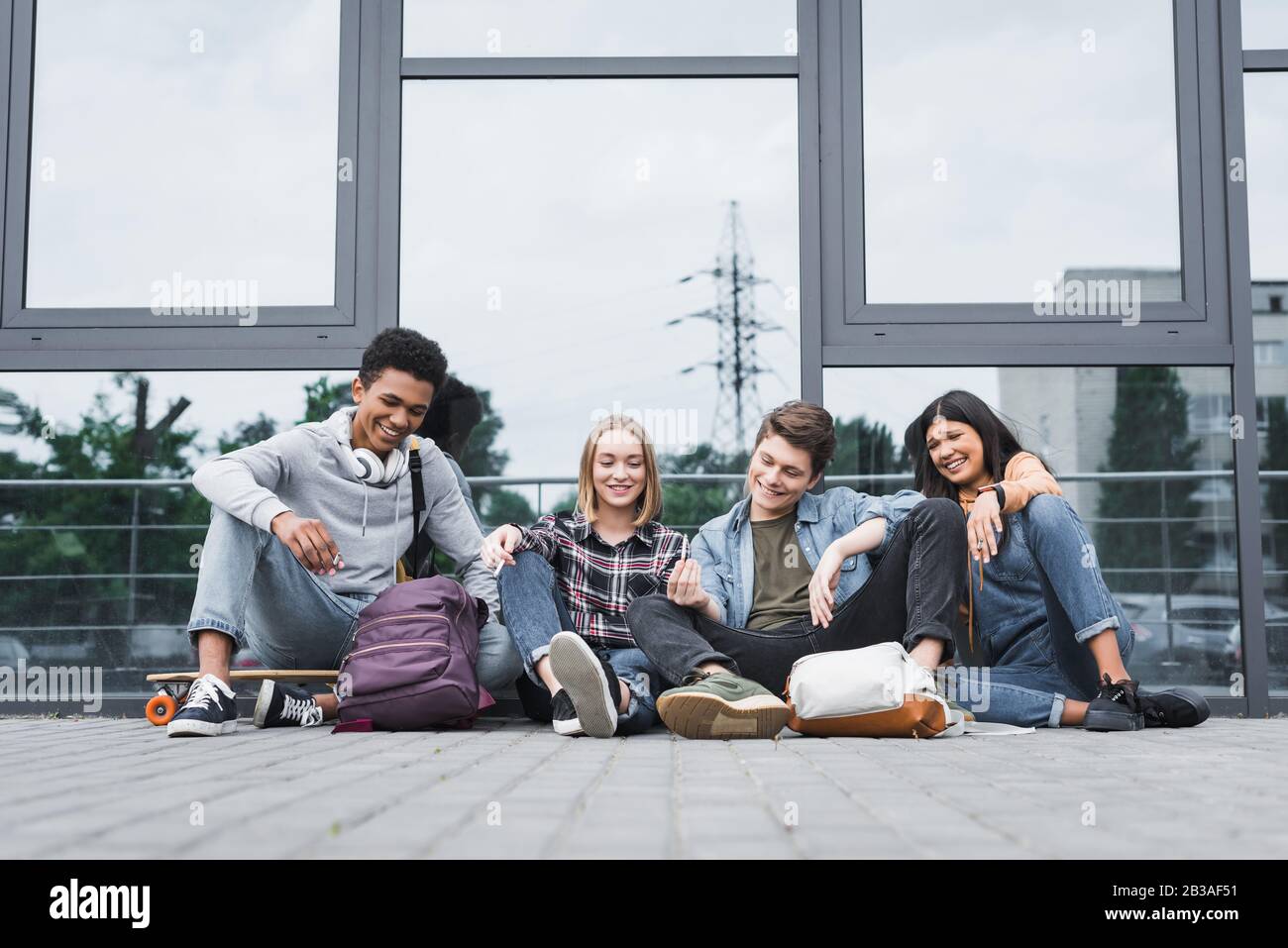 happy and positive friends smiling, sitting and smoking cigarettes ...