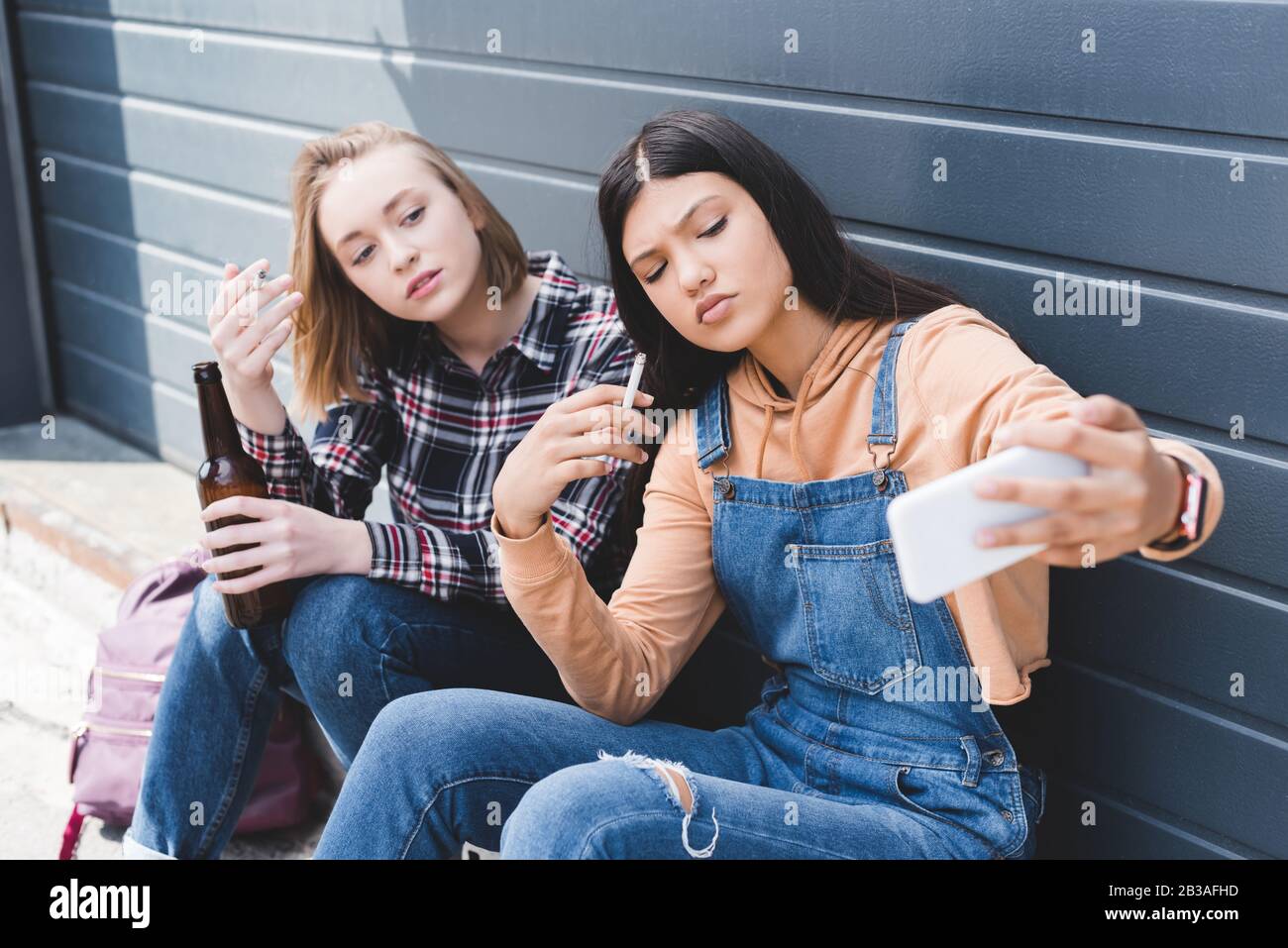 selective focus of friends smoking cigarettes, holding beer and taking ...