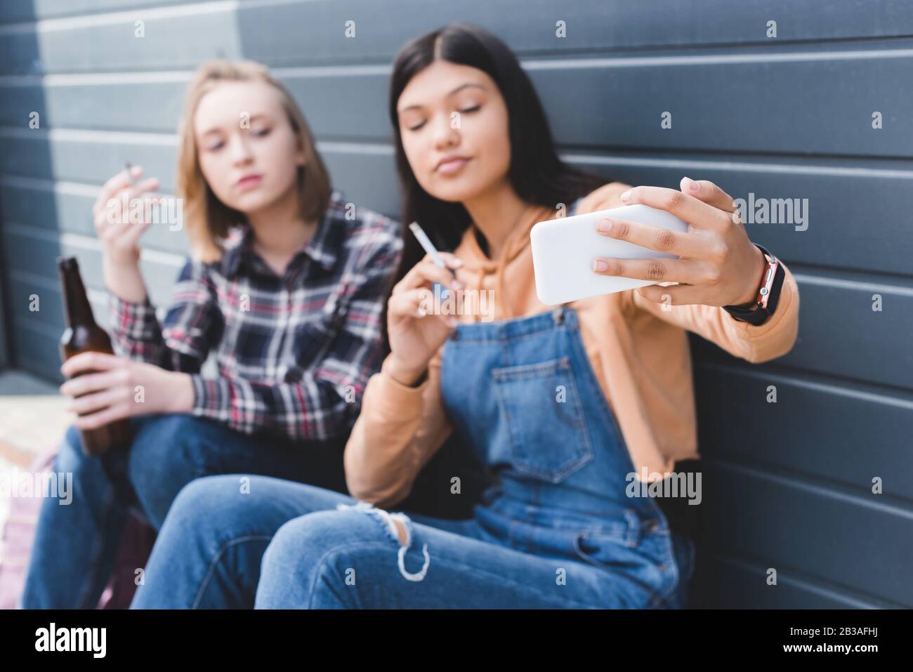 selective focus of friends smoking cigarettes, holding beer and taking ...