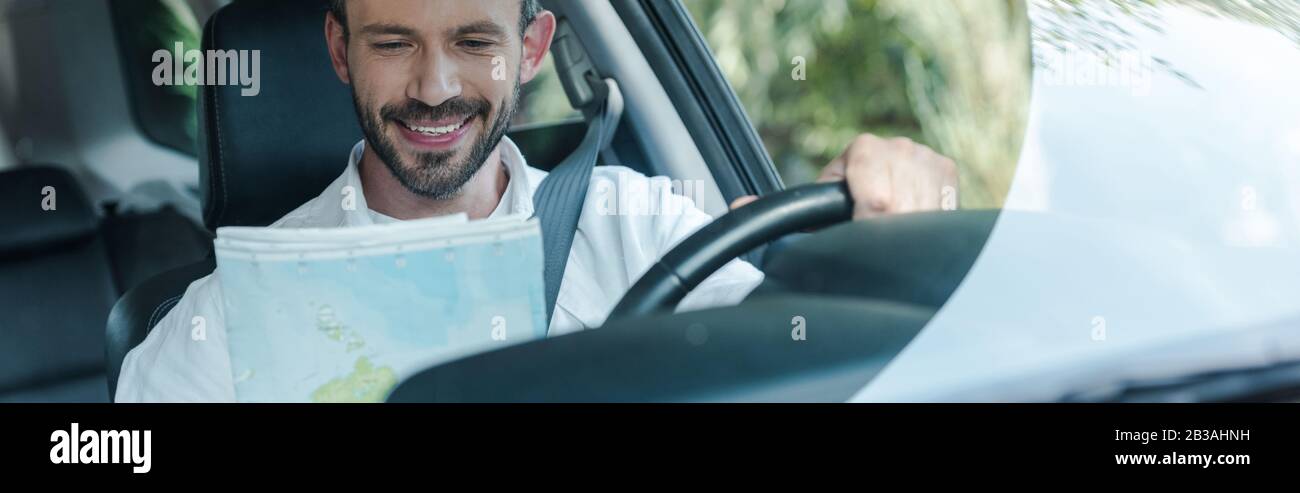 panoramic shot of happy driver sitting in car and looking at map Stock ...