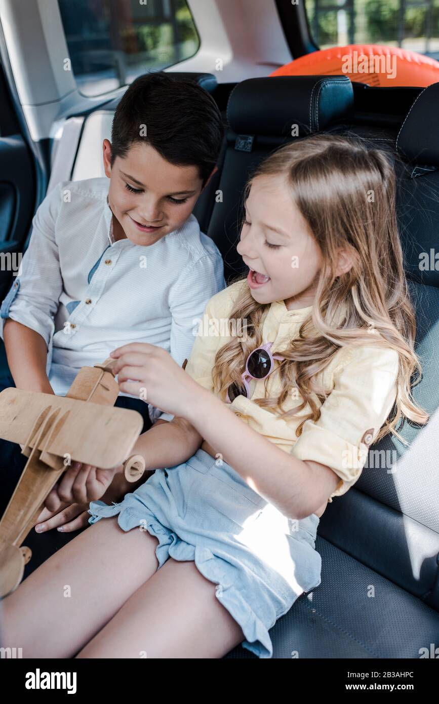 happy sister and brother playing with wooden toy biplane in car Stock ...