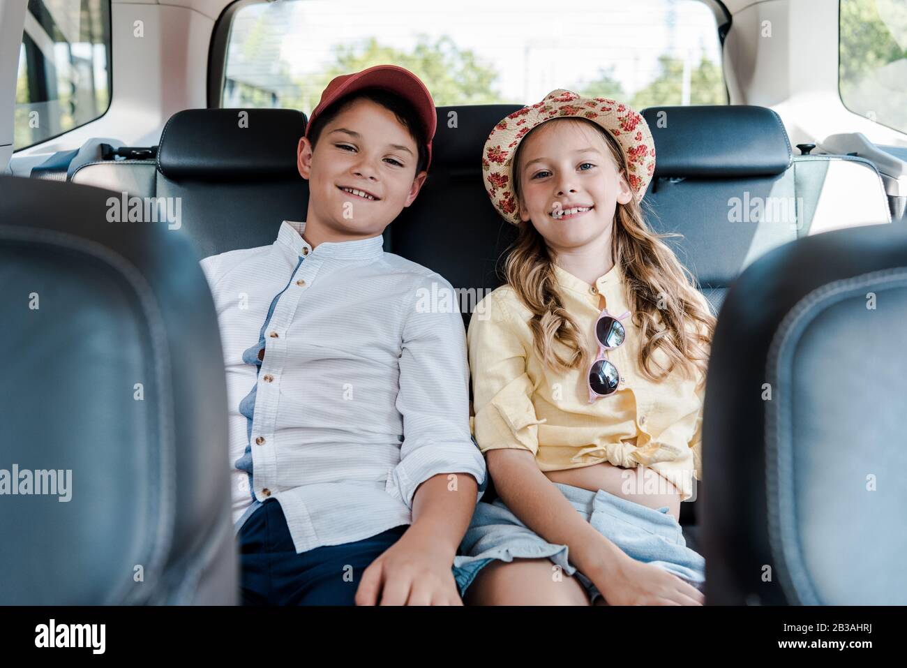 selective focus of happy sister and brother smiling while sitting in ...