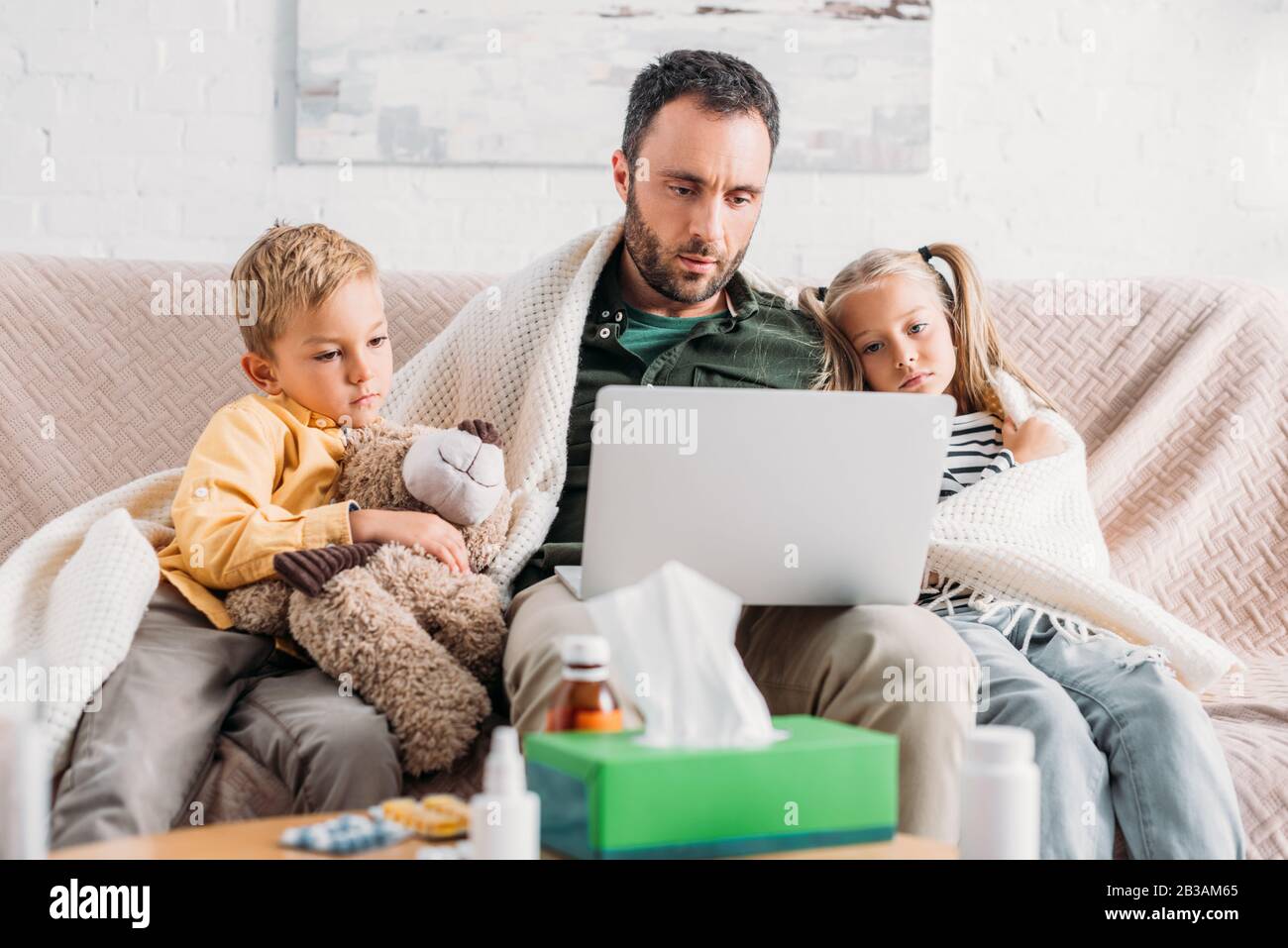 diseased children sitting on sofa near sick father using laptop Stock ...