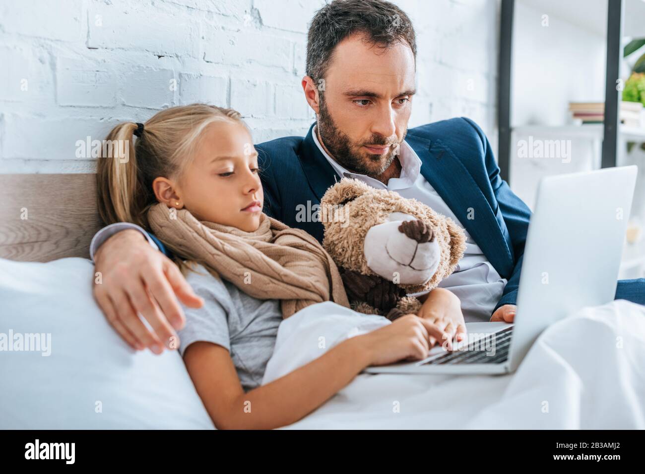 sick child using laptop with father while lying in bed Stock Photo - Alamy