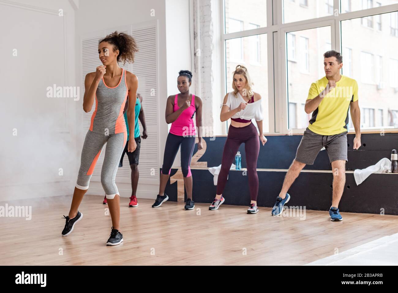 Beautiful african american trainer performing zumba movements with ...