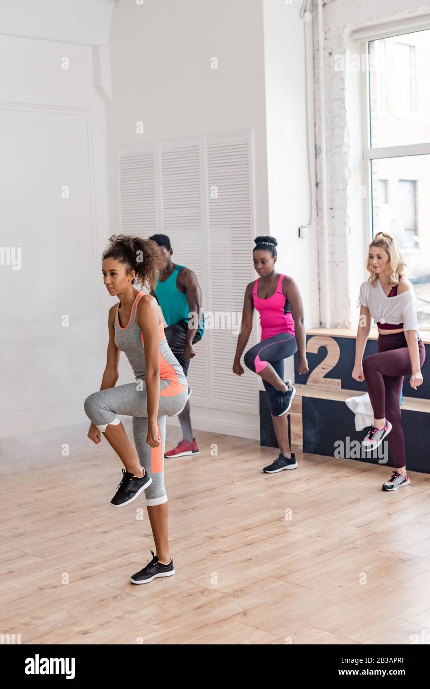 Attractive african american trainer performing zumba with multicultural ...