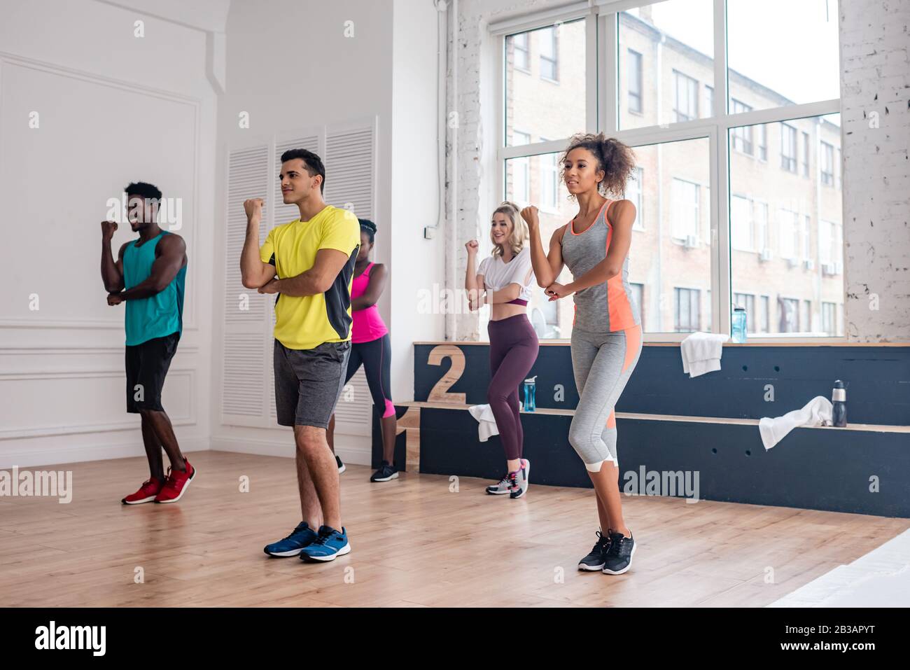 Smiling multicultural dancers performing zumba movements in dance ...