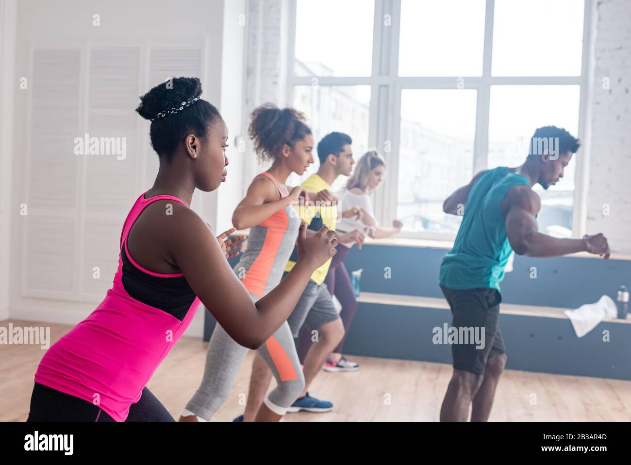 Side view of multicultural dancers learning movements of zumba with ...