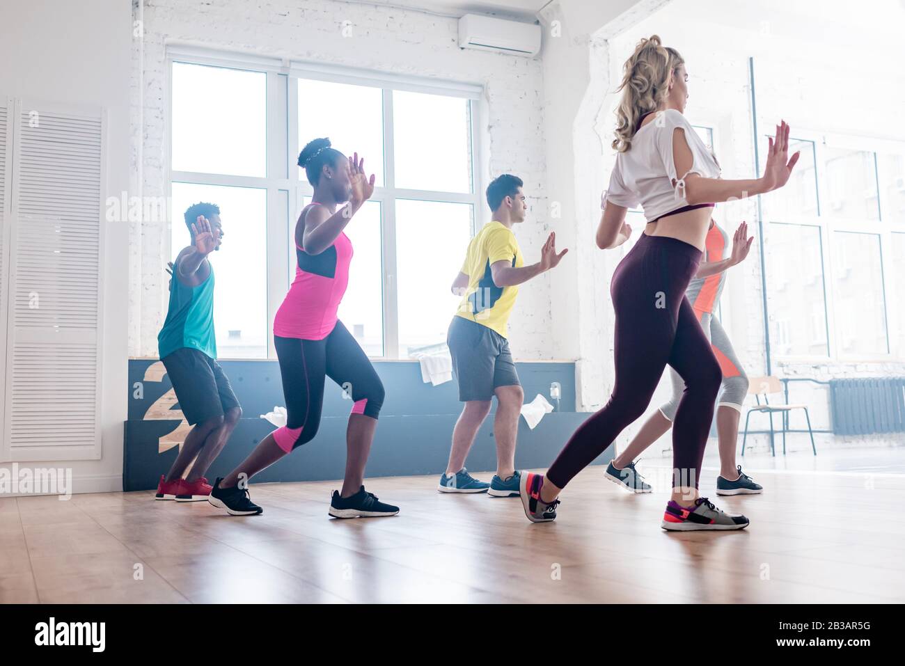 Side view of multicultural zumba dancers training together in studio ...