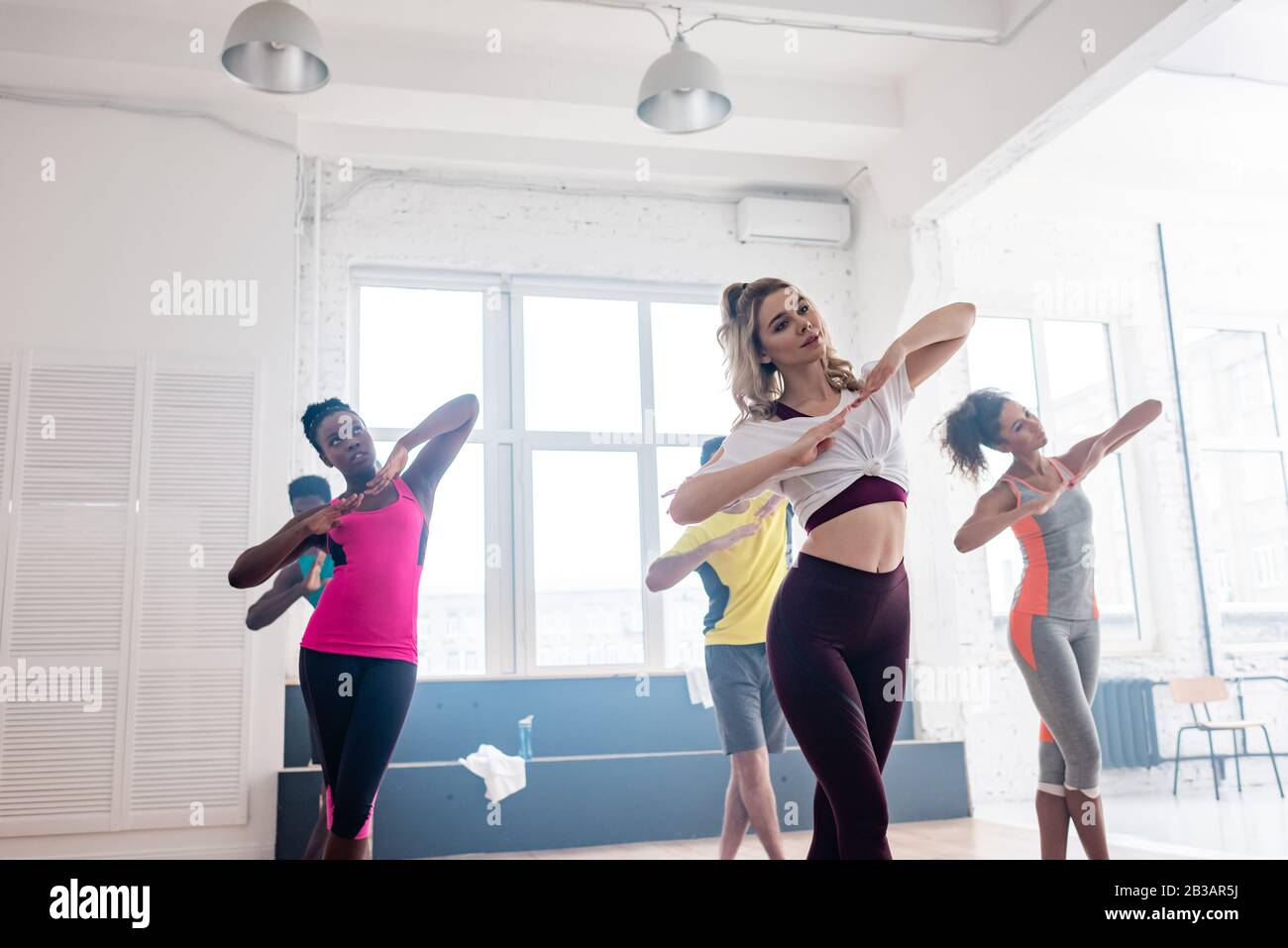 Beautiful trainer performing zumba with multicultural dancers in dance ...