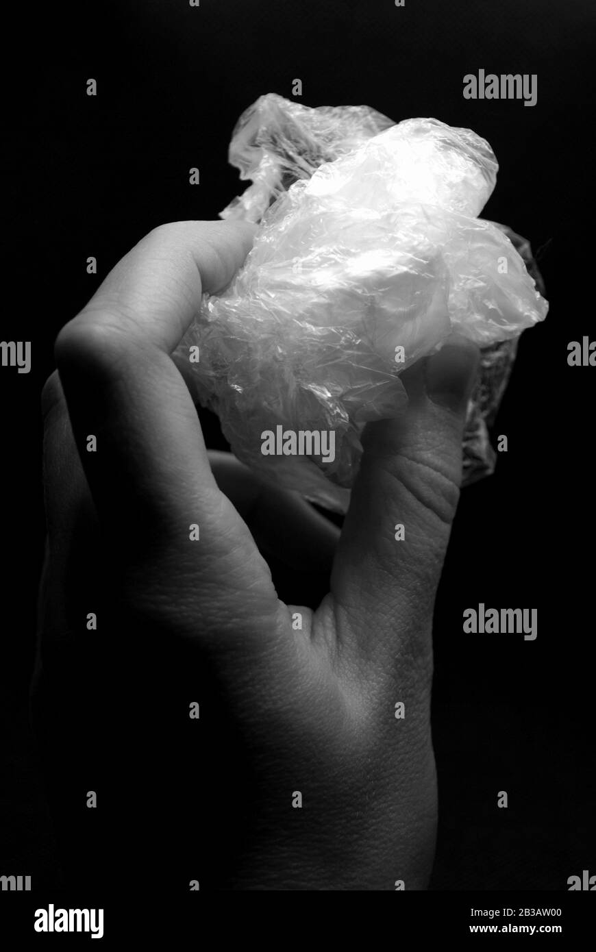 Black and white photograph of hand holding crushed white transparent ...