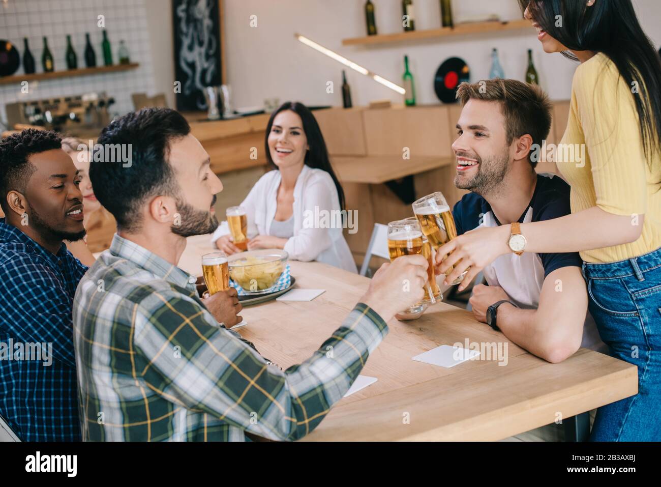 cheerful multicultural friends talking while drinking beer in pub Stock ...