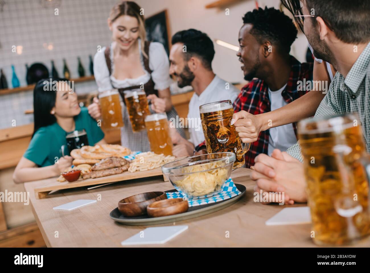 selective focus of waitress in traditional german costume serving beer ...