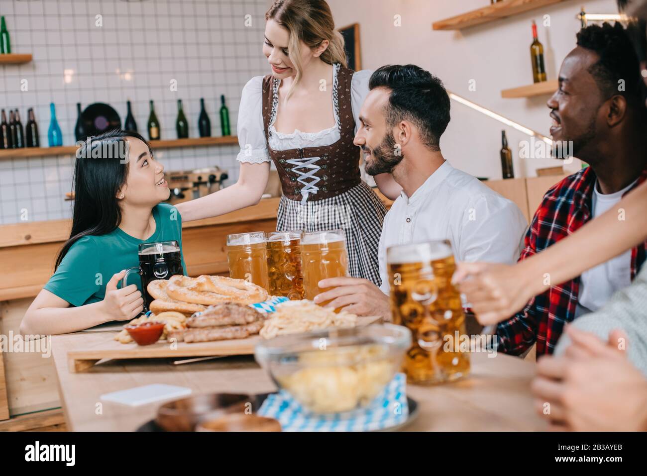 attractive waitress in traditional german costume serving beer for ...