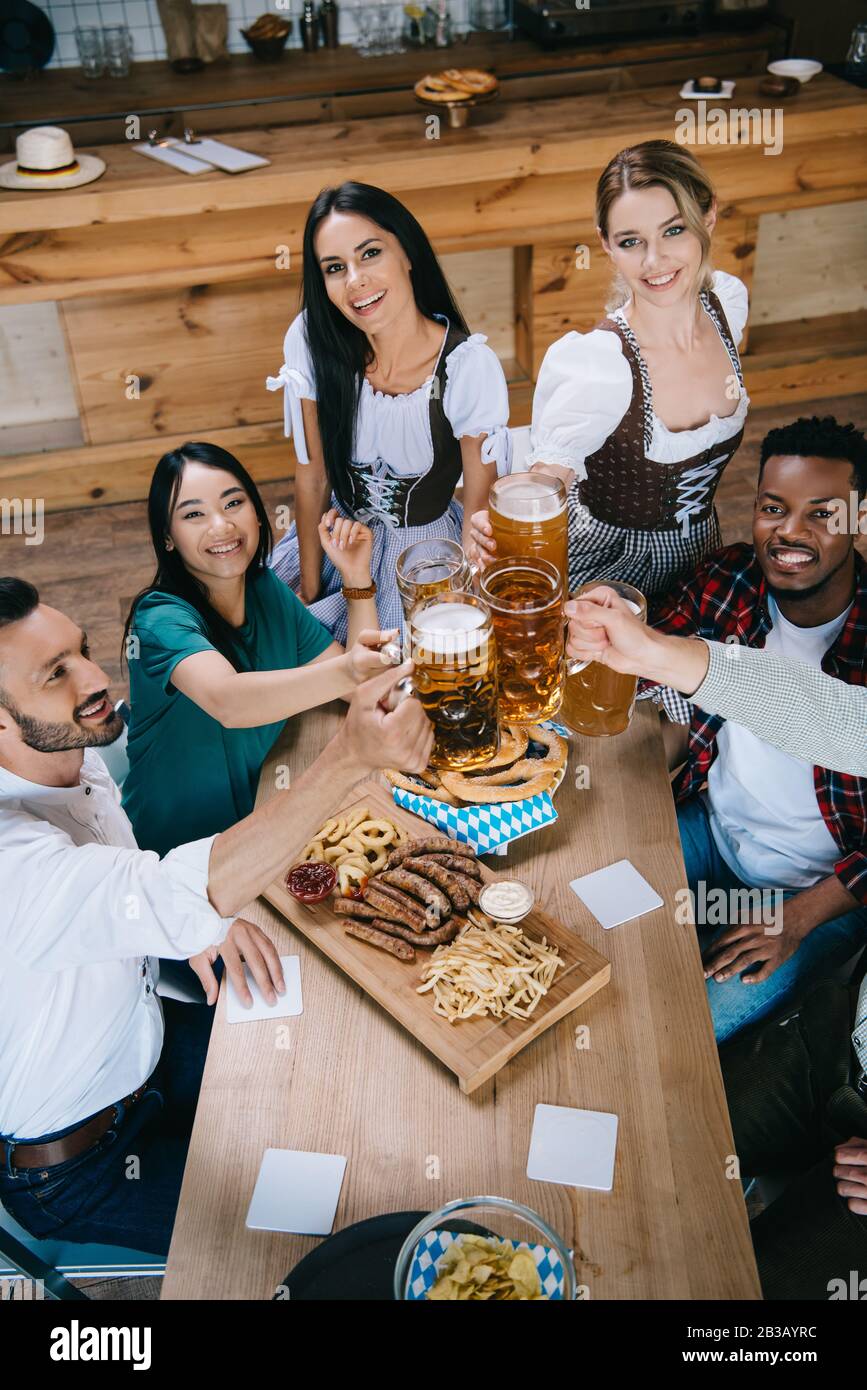 beautiful waitresses in traditional german costumes clinking mugs of ...