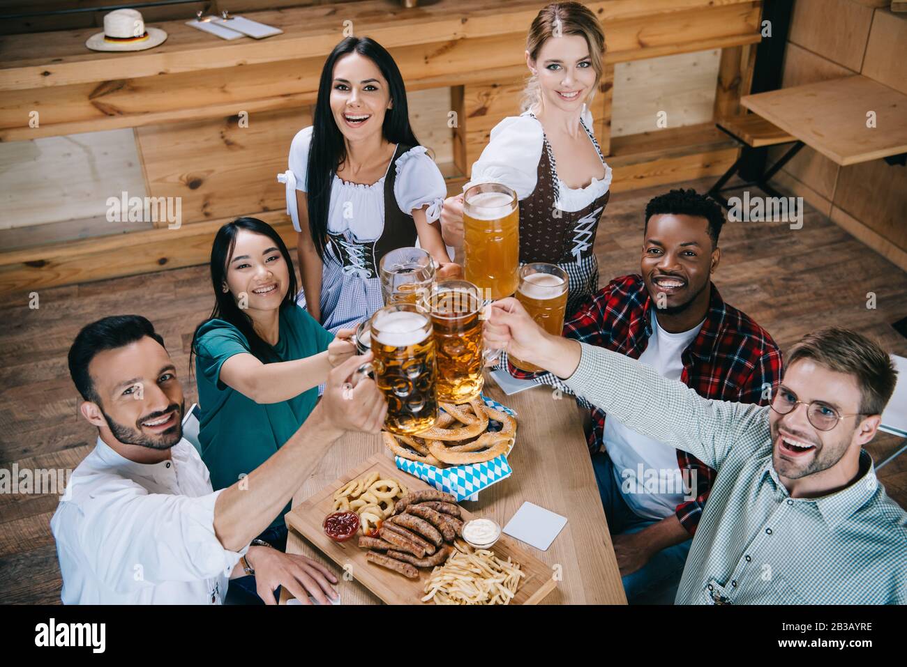 attractive waitresses in traditional german costumes clinking mugs of ...