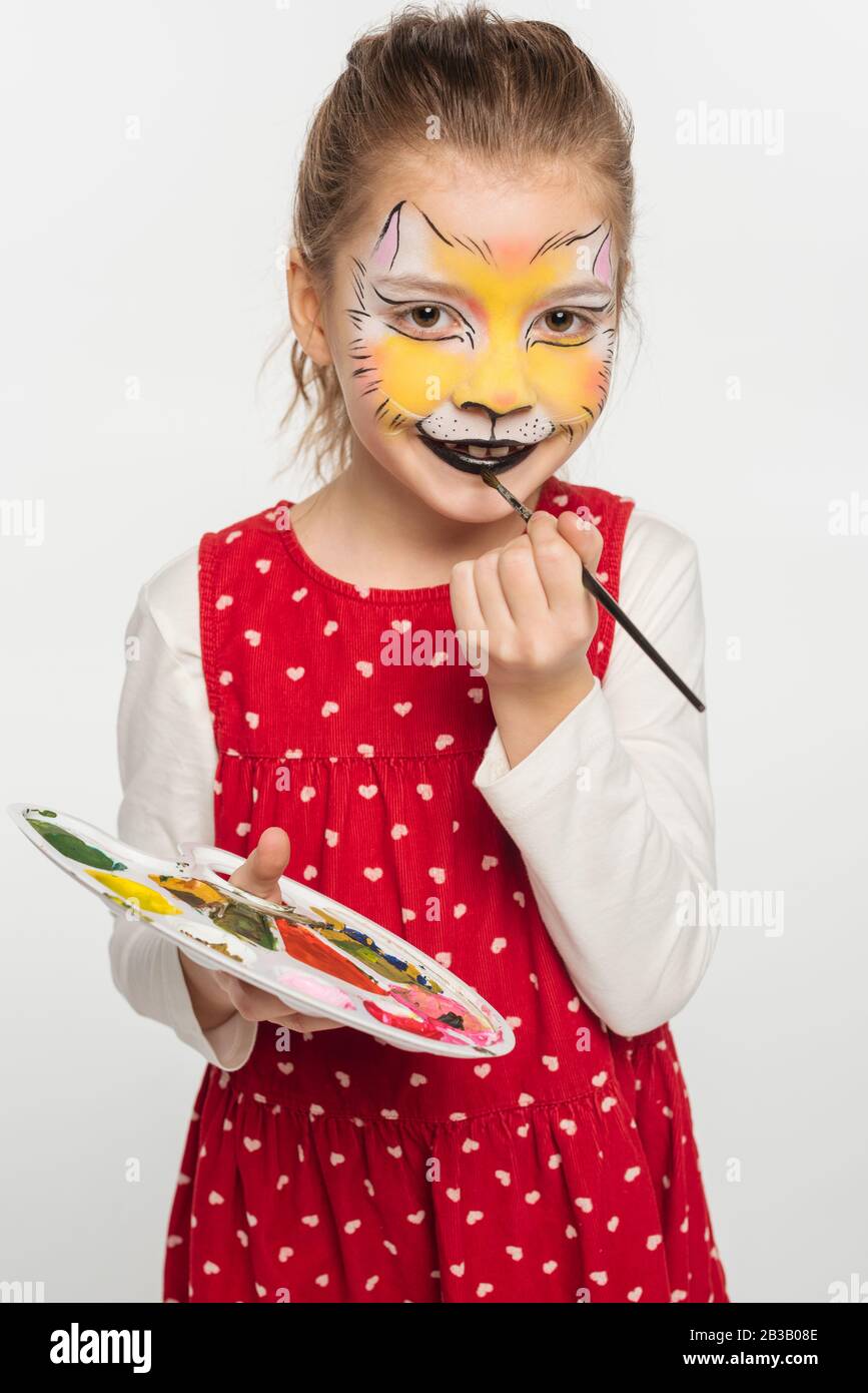 smiling kid with tiger muzzle painting on face holding palette while ...