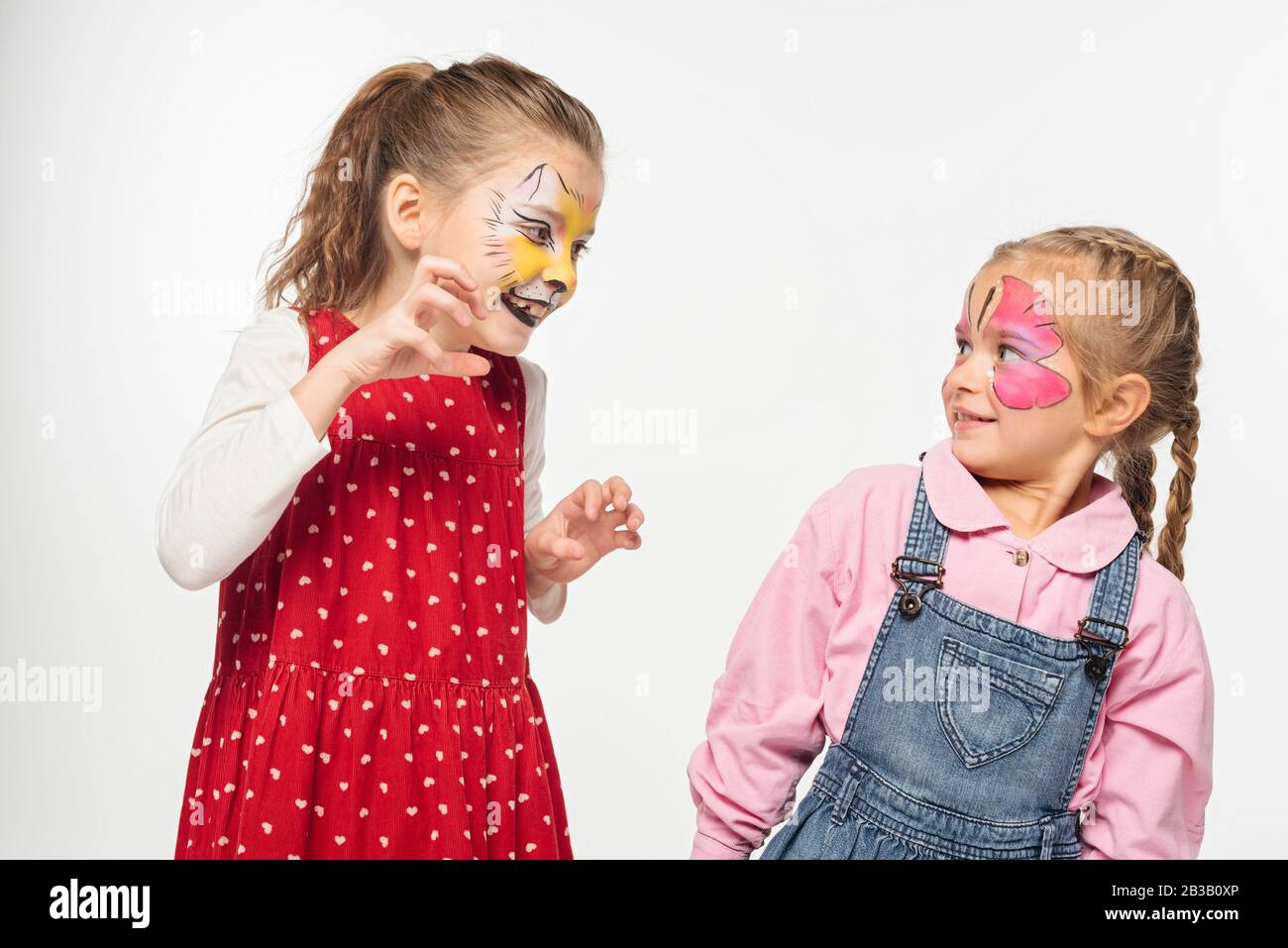 cheerful kid with cat muzzle painting on face scaring friend isolated ...