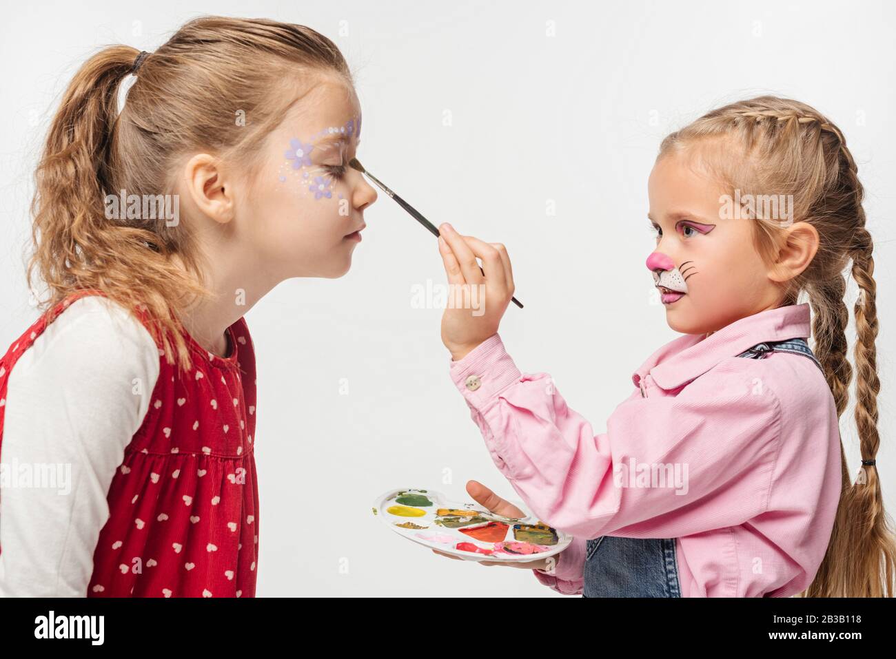 cute kid with painted cat muzzle painting floral pattern on face of ...