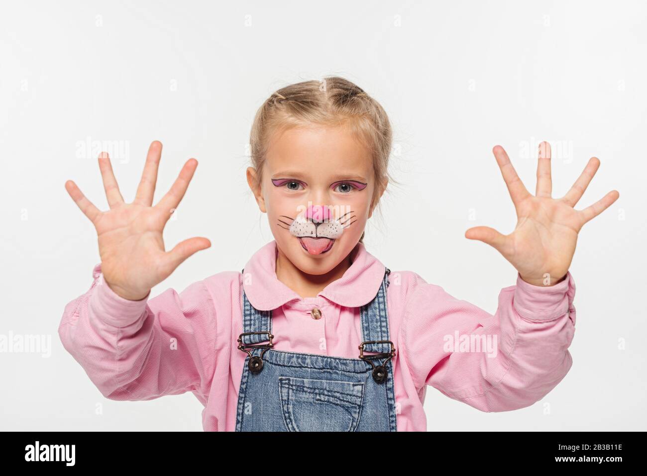 cheerful child with cat muzzle painting on face showing palms while ...