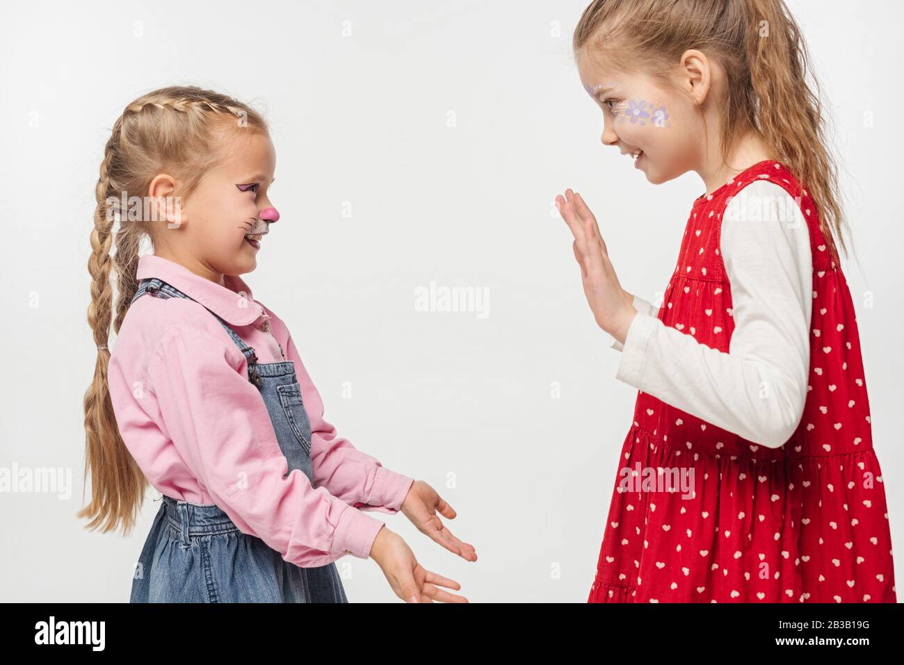 excited friends with cat muzzle and floral paintings on faces clapping ...