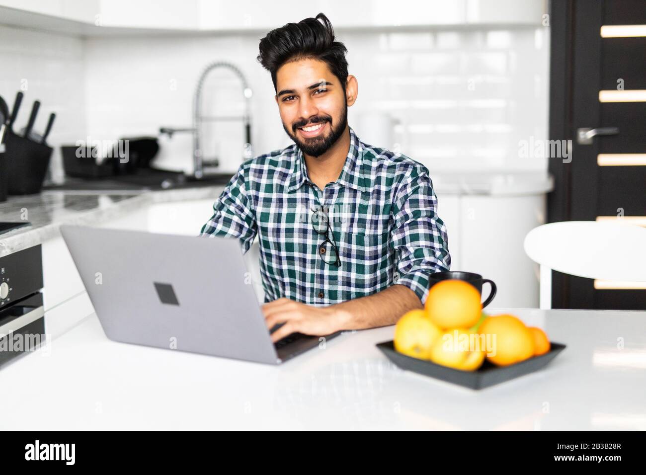 Handsome man using a laptop pc in the kitchen Stock Photo - Alamy