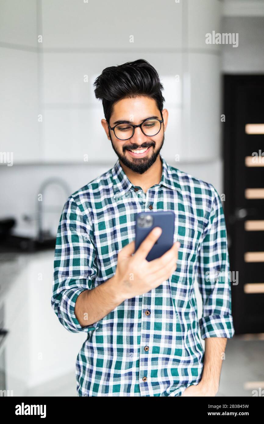 Happy indian man texting on the phone in kitchen Stock Photo - Alamy