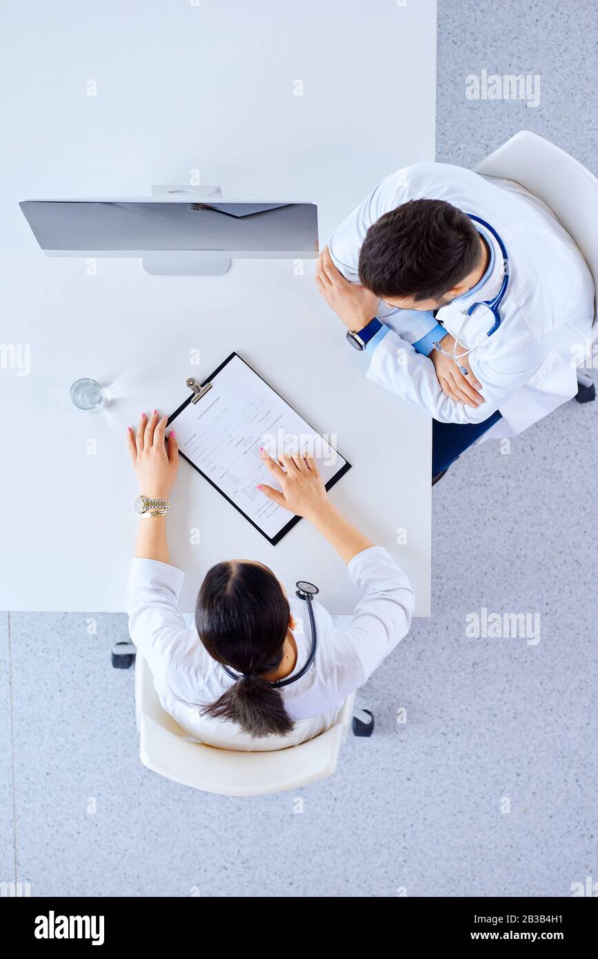 Doctors discussing a patient’s diagnosis in an office at a table in ...
