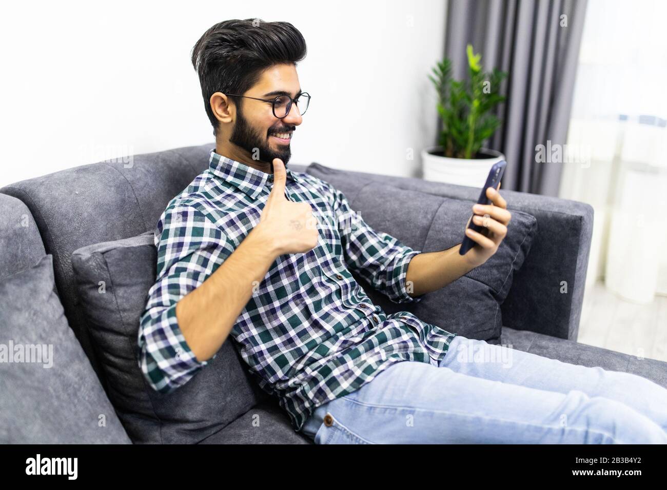 Young indian man have video call conversation on the phone lying at ...