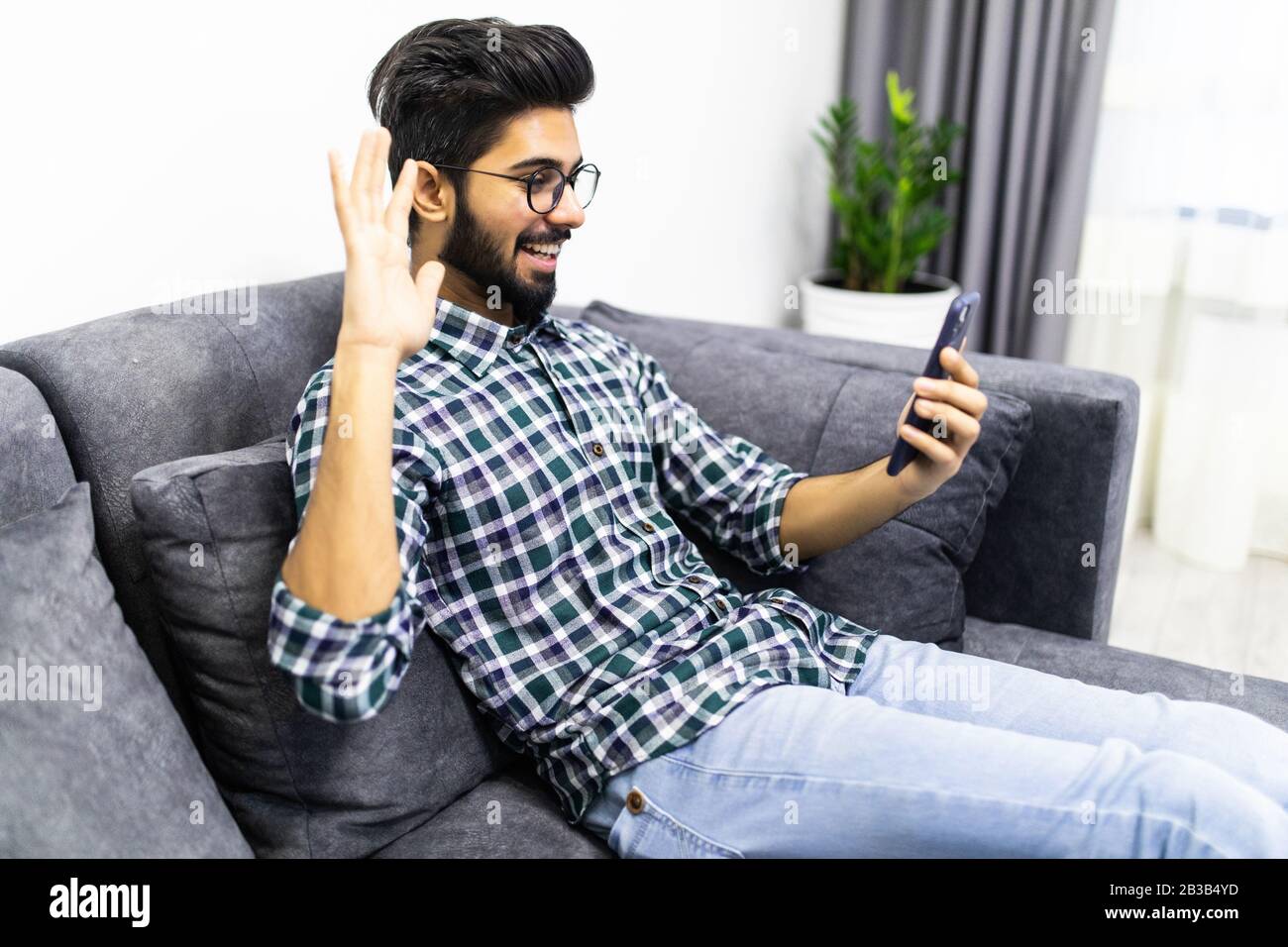 Young indian man have video call conversation on the phone lying at ...