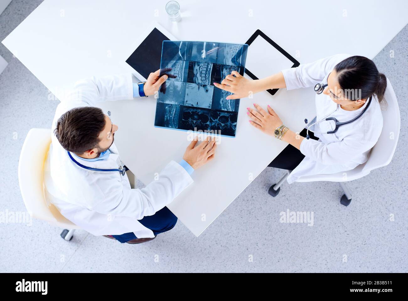 Medical team of doctors sitting and discussing about x-ray at table ...