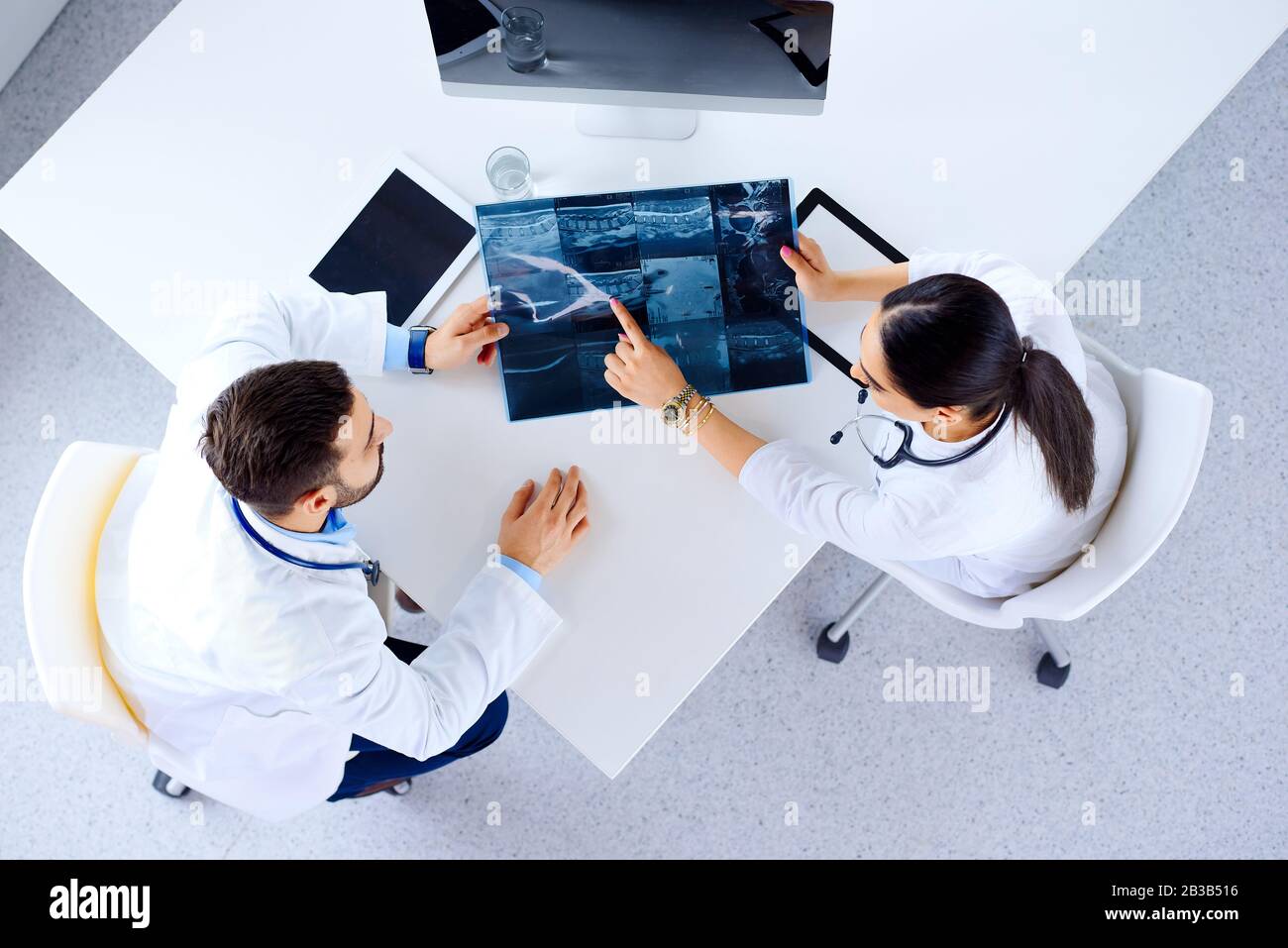 Medical team of doctors sitting and discussing about x-ray at table ...