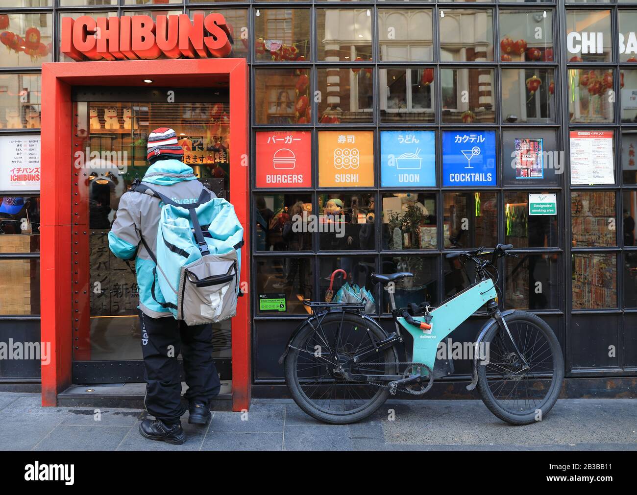 Deliveroo cyclist picking up delivery on Wardour Street, in London's ...