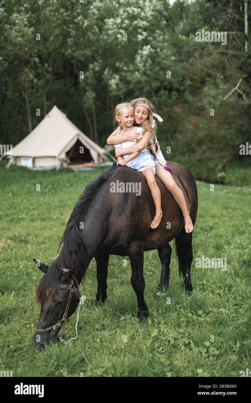 Horseback, two children girls, sisters, riding a horse outdoors ...