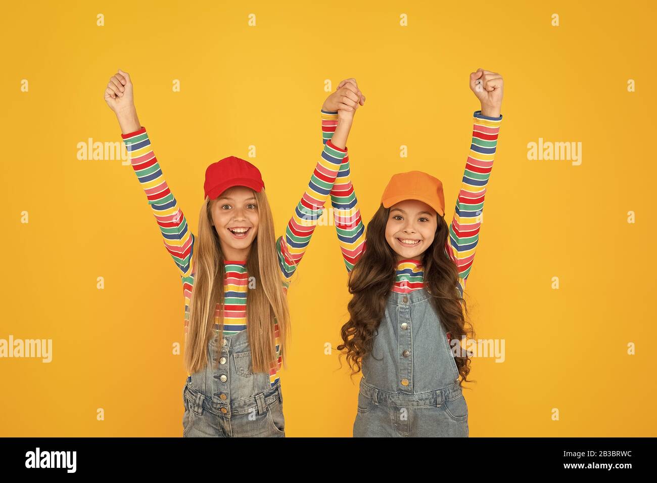 Celebrating victory. Happy girls celebrating achievement on yellow ...