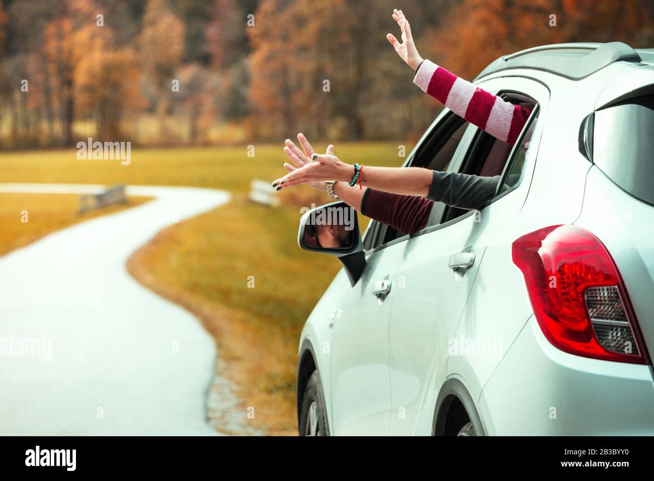 hands of men and girl peering out of a car window on a background of ...