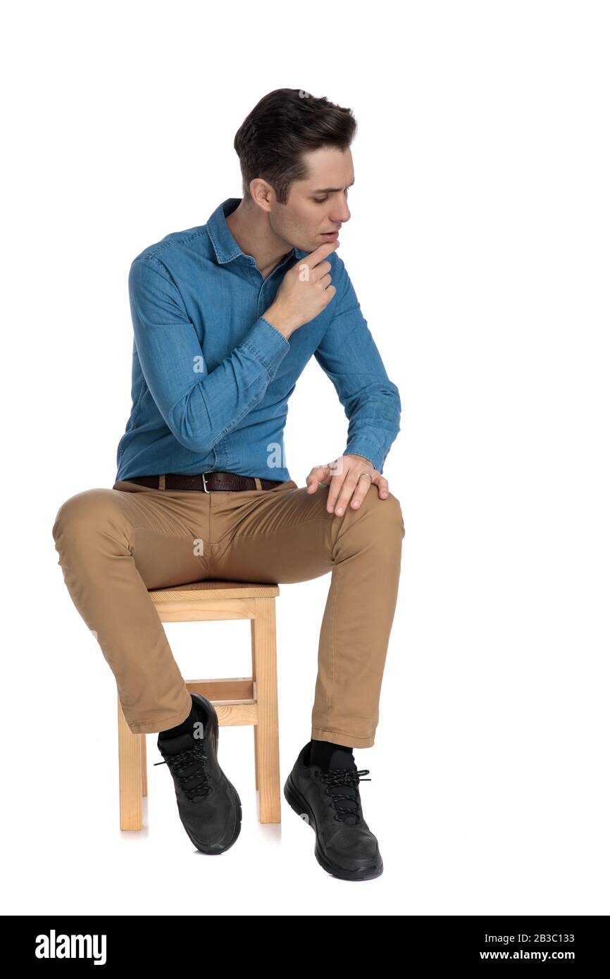 thoughtul young man touching chin and thinking, looking down and ...