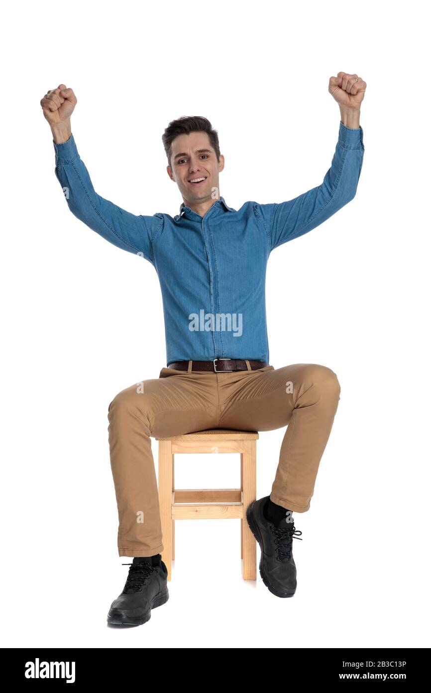 excited young man holding arms in the air and celebrating victory ...