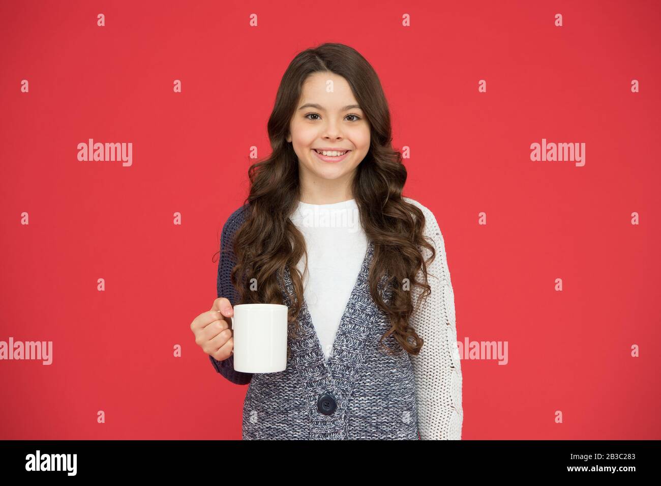 Good morning. Drink enough water. Girl kid hold mug red background ...