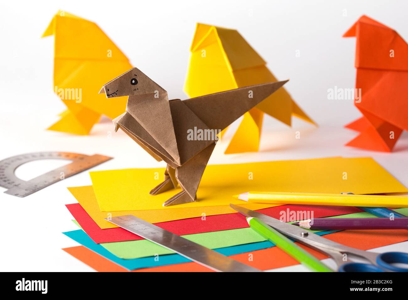 origami bird and dinosaur made of colored paper. paper, ruler, pencils ...