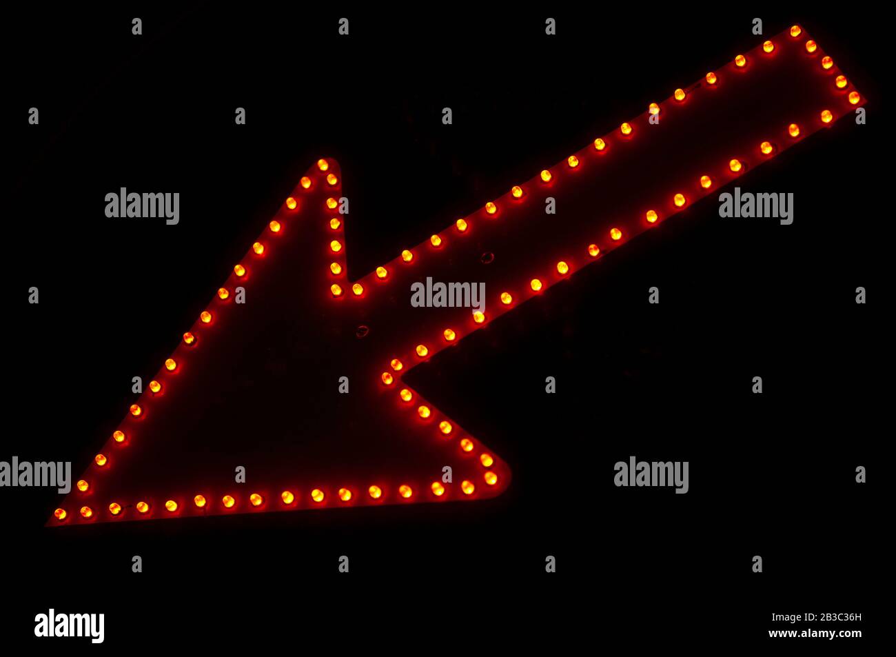 Red arrow sign formed from silhouette of small lumiere lights on dark ...