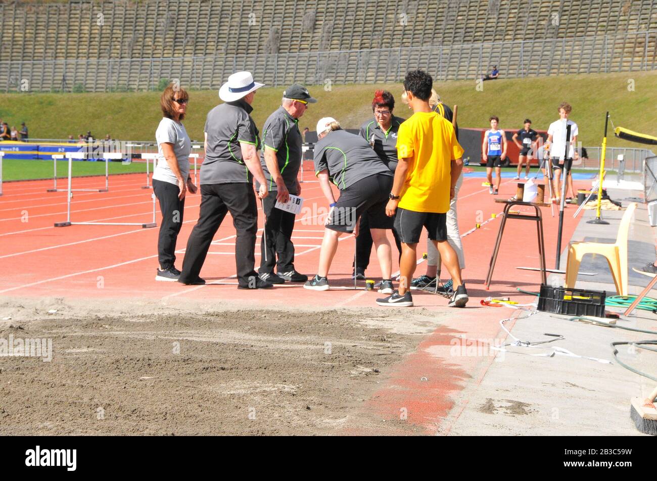 Track officials at the long jump confer about precise measurement at an ...