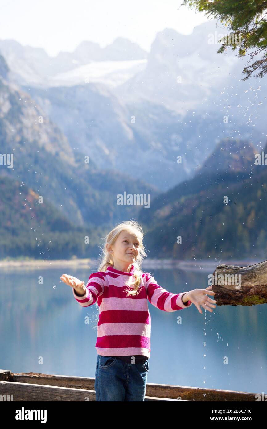 landscape with a beautiful mountain lake. girl drinks water from wooden ...