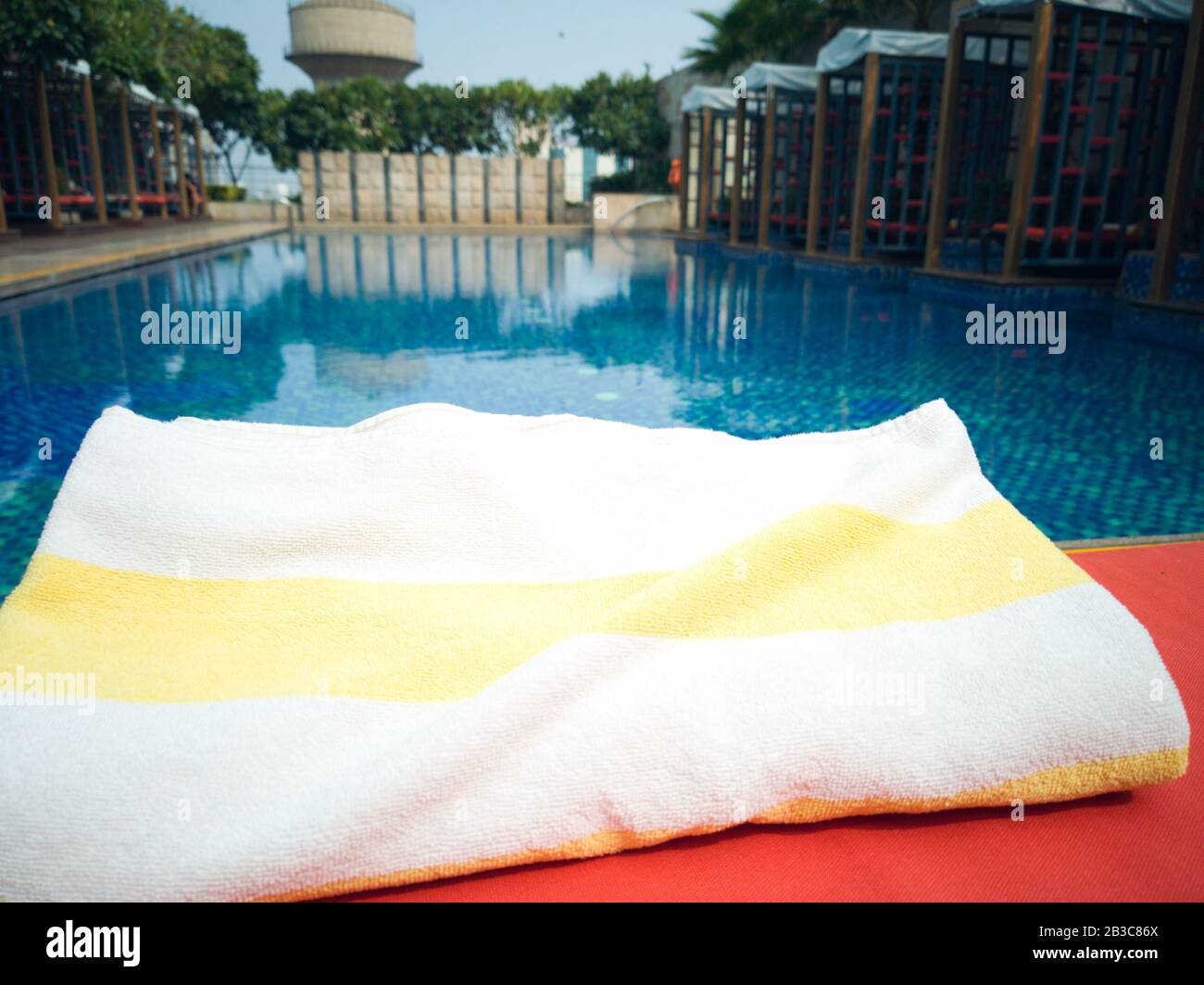Yellow and white coloured towel on the poolside of a calm beautiful ...