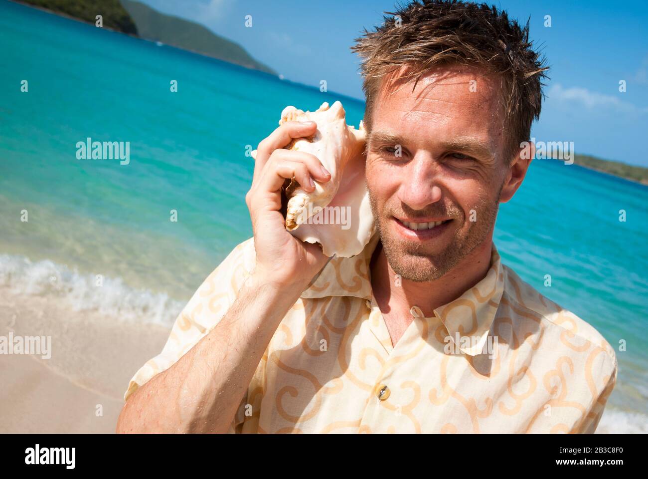 smiling man standing on tropical beach having an imaginary conversation ...
