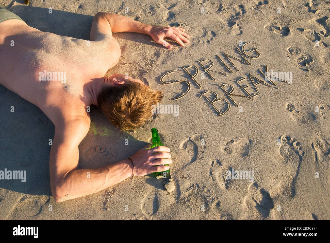 Shirtless guy passed out on the beach with beer bottle next to Spring ...