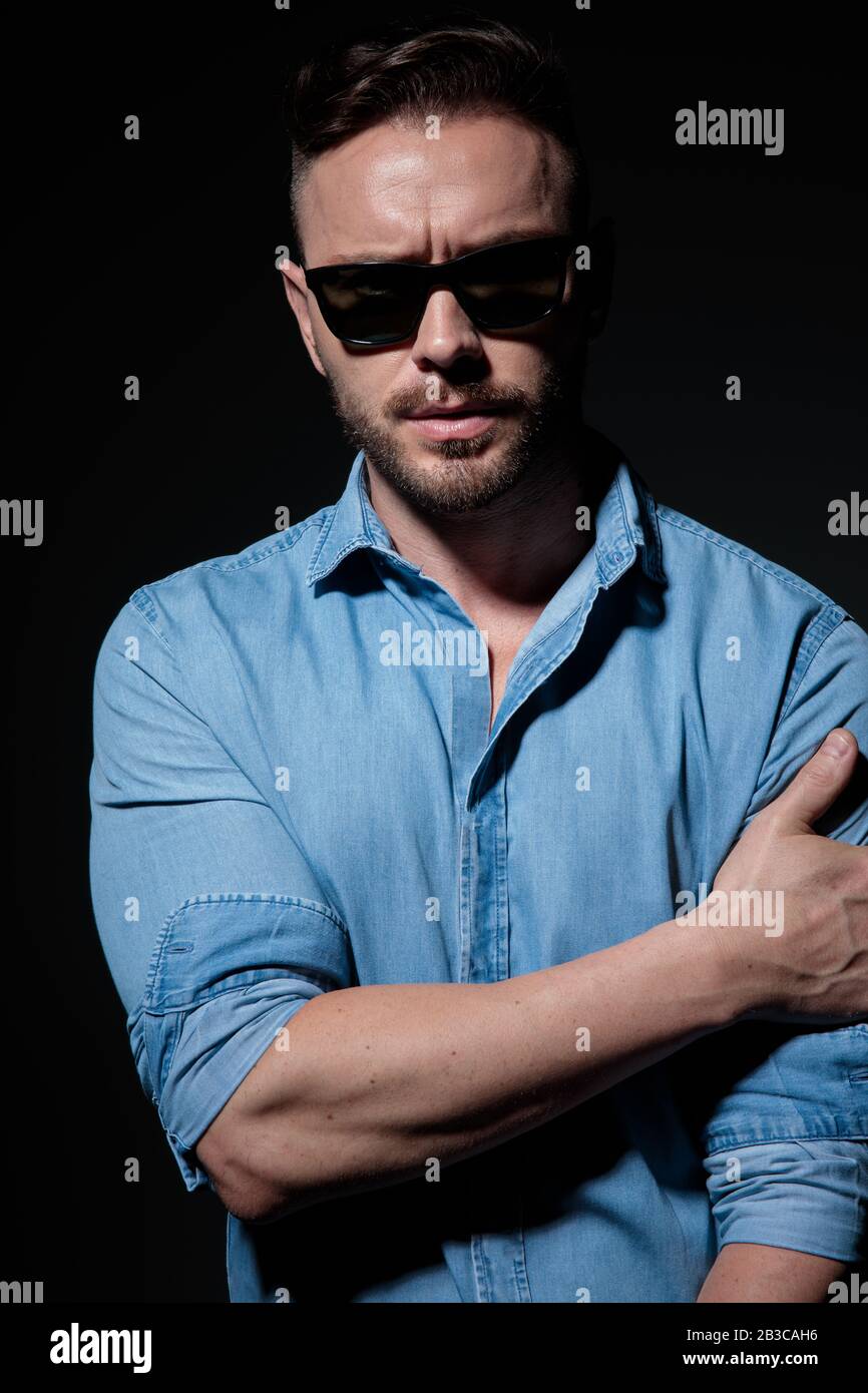 good looking casual man wearing blue shirt and sunglasses standing with ...