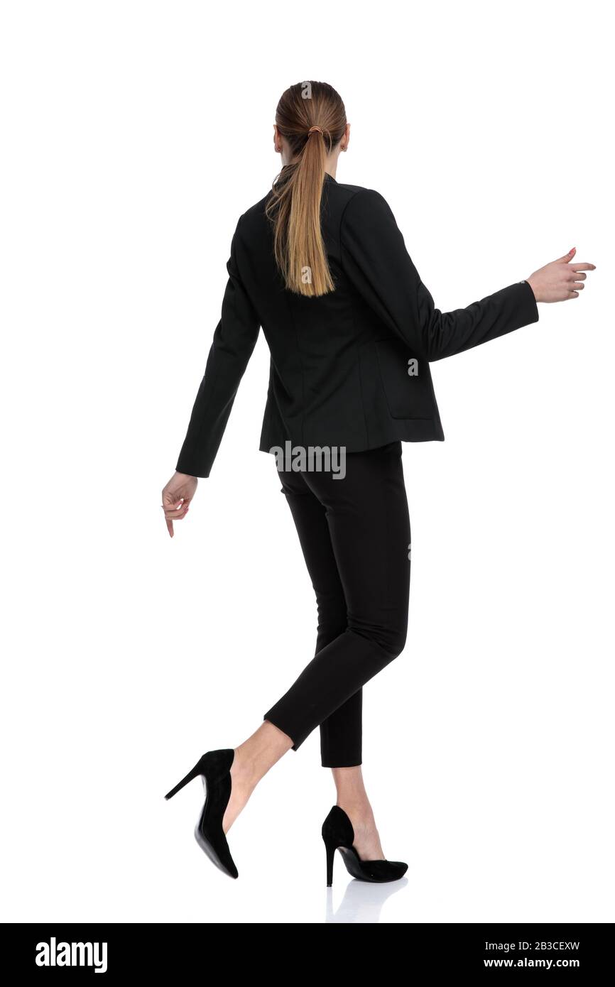 rear view of a young businesswoman wearing black suit posing with hands ...